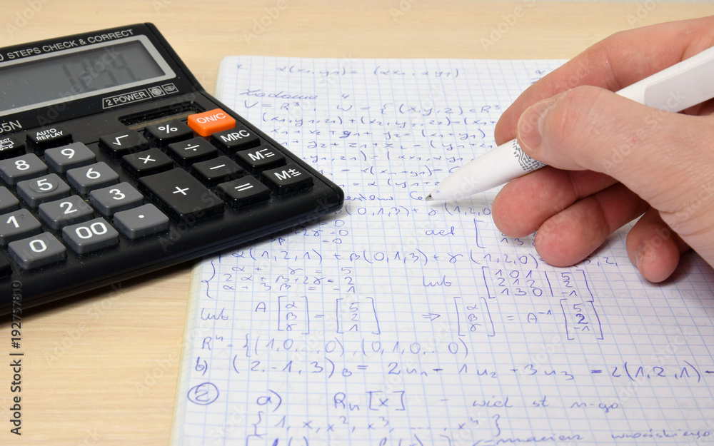 Solving math problems. Calculator, pen, hand. Stock Photo | Adobe Stock