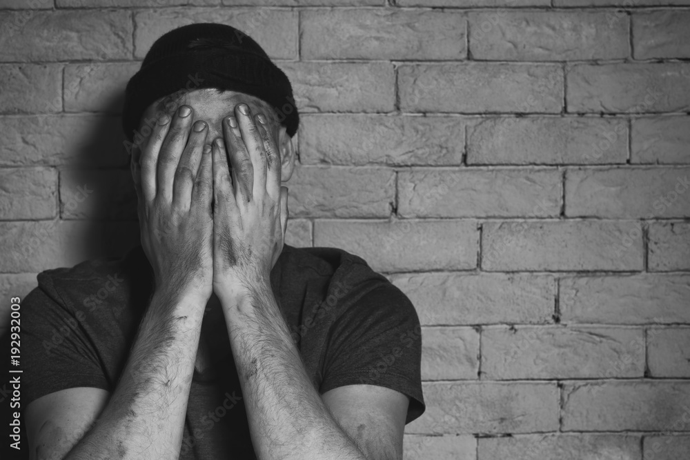 Hungry poor man crying near brick wall Stock Photo | Adobe Stock