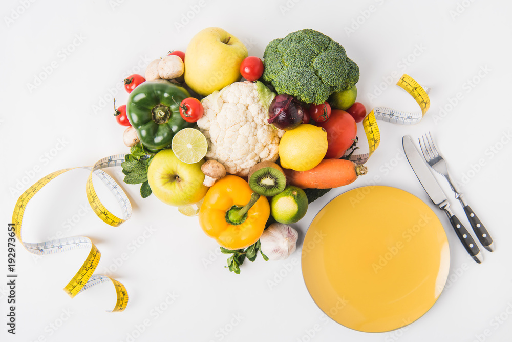 vegetables and fruits laying on white background with fork, spoon ...