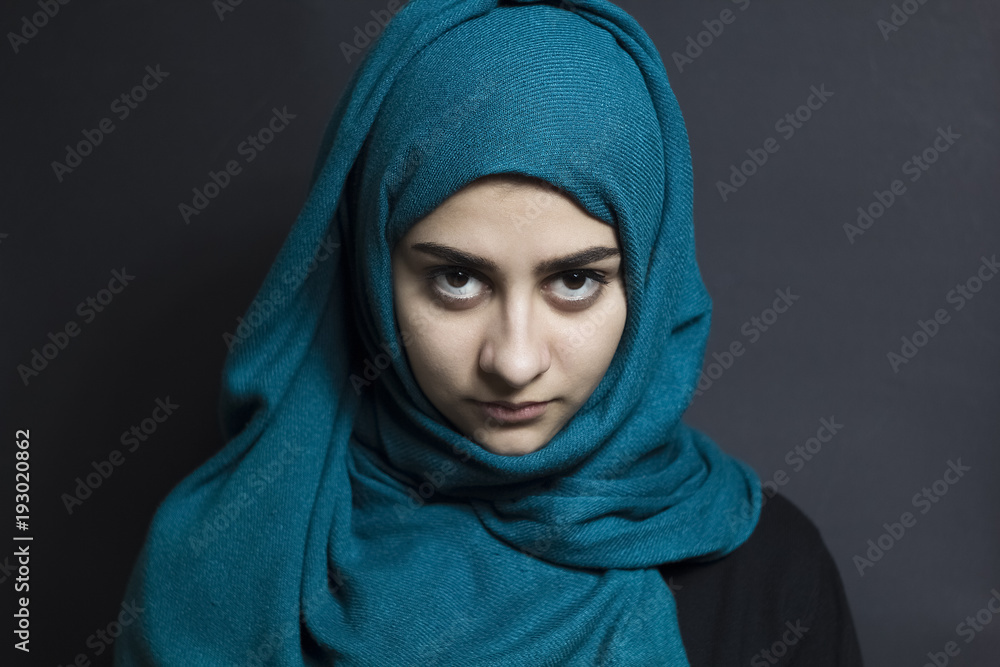 Portrait of a sad Arab girl in a hijab on a black background. Muslim ...