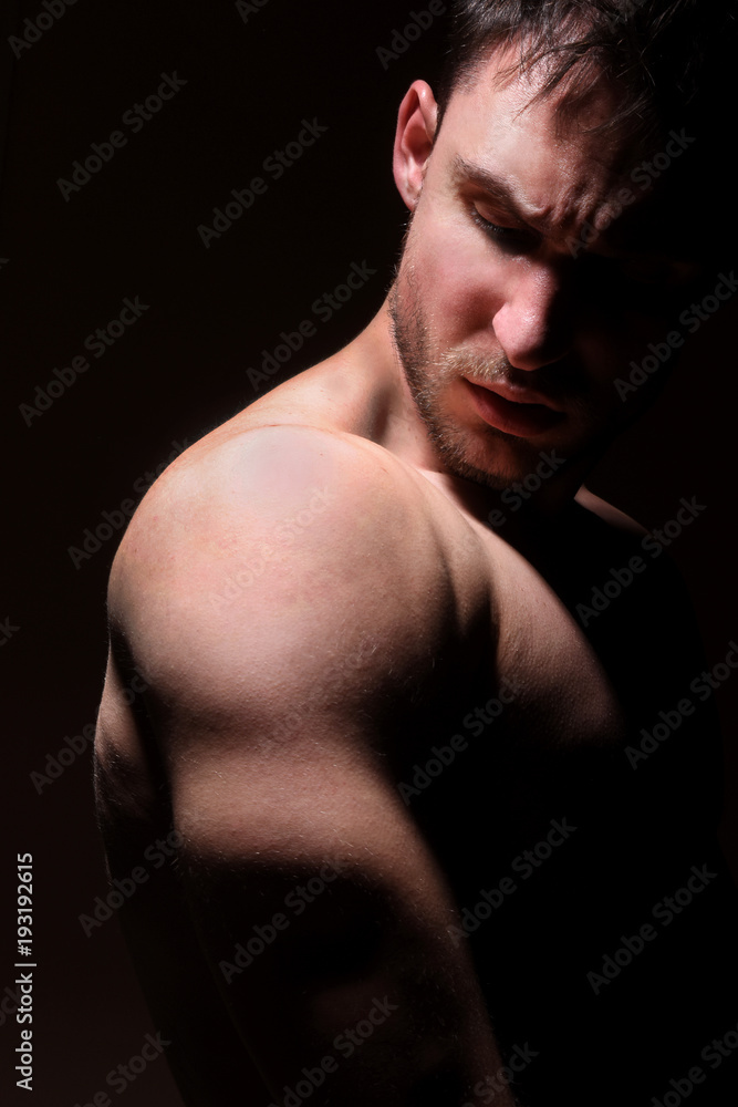 Big and strong muscular man in posing in a low light. Fitness model or ...