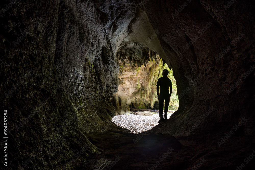 Silhoutte of Hiker in huge mysterious cave, Oparara Basin, Moria Gate ...