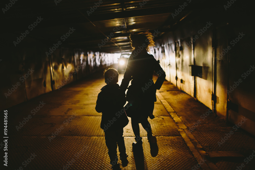 Woman and kid running away through tunnel Stock Photo | Adobe Stock
