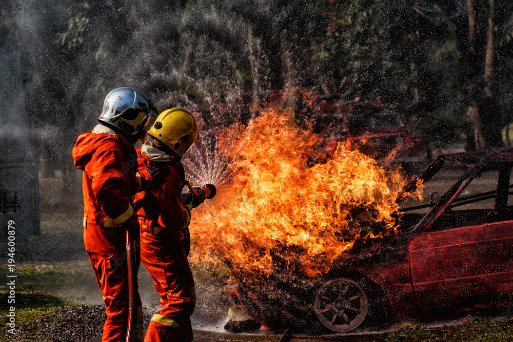 Firefighter in fire fighting suit spraying water, Firemen fighting ...