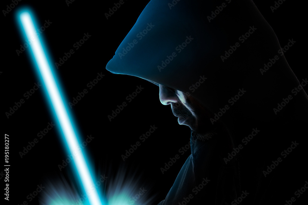 Man in hood / Hooded man in shadow with light sword on black background ...