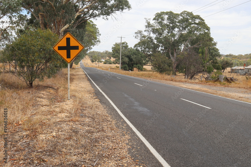 yellow sign with black cross indicating Crossroads Ahead on a country ...