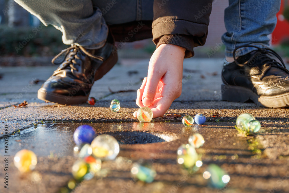 Child playing with marbles on yhe sidewalk. old-fashioned toys still in ...
