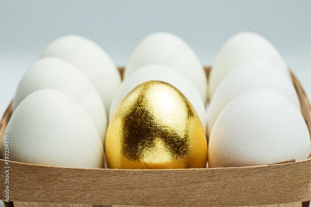 One golden egg among white eggs in a wooden box. Uniqueness concept. の ...