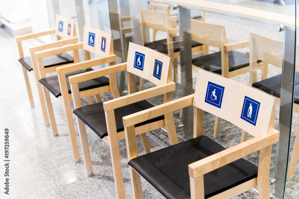 four wooden chairs at the airport with signs for the disabled and the ...