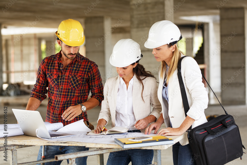 Two female inspectors and architects discuss with head engineer about construction project ...
