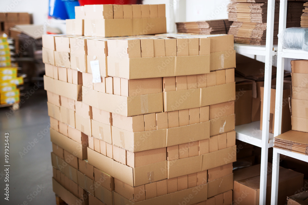 Big stack of brown boxes next to shelves with stacks of folded boxes ...