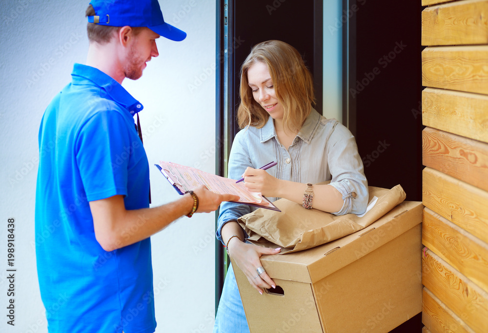 Smiling delivery man in blue uniform delivering parcel box to recipient ...