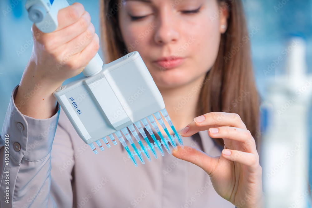 student woman with multi pipette and other PCR items in microbiological ...