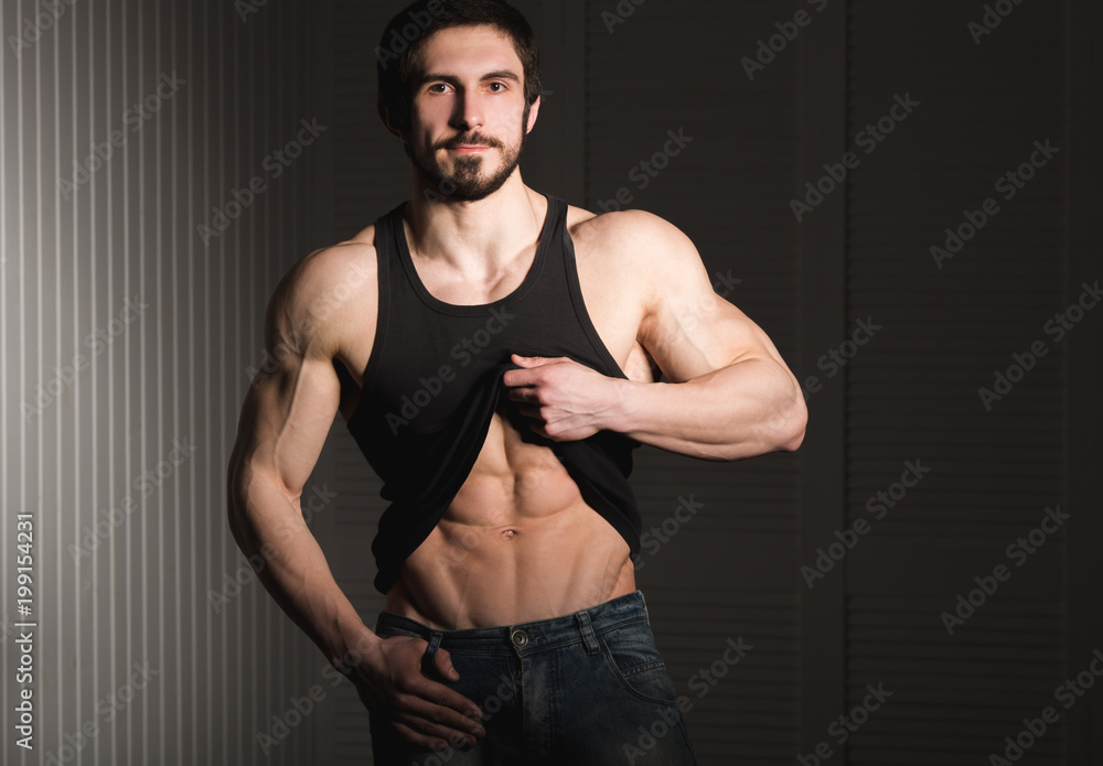 Perfect man shows his six pack abs. Muscular and fit torso of young male. Hunk with athletic ...