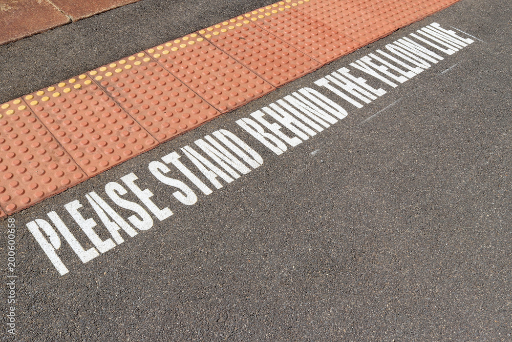 Please Stand Behind The Yellow Line warning in stencilled white paint ...
