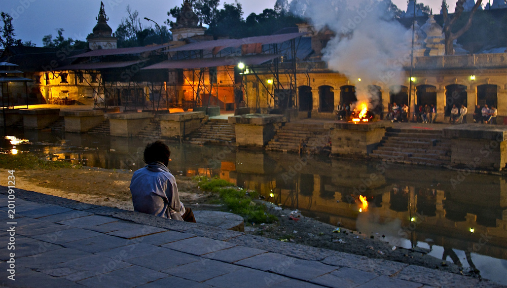 A lonely man looks at the funerary fire. Funeral ceremony in Nepal ...