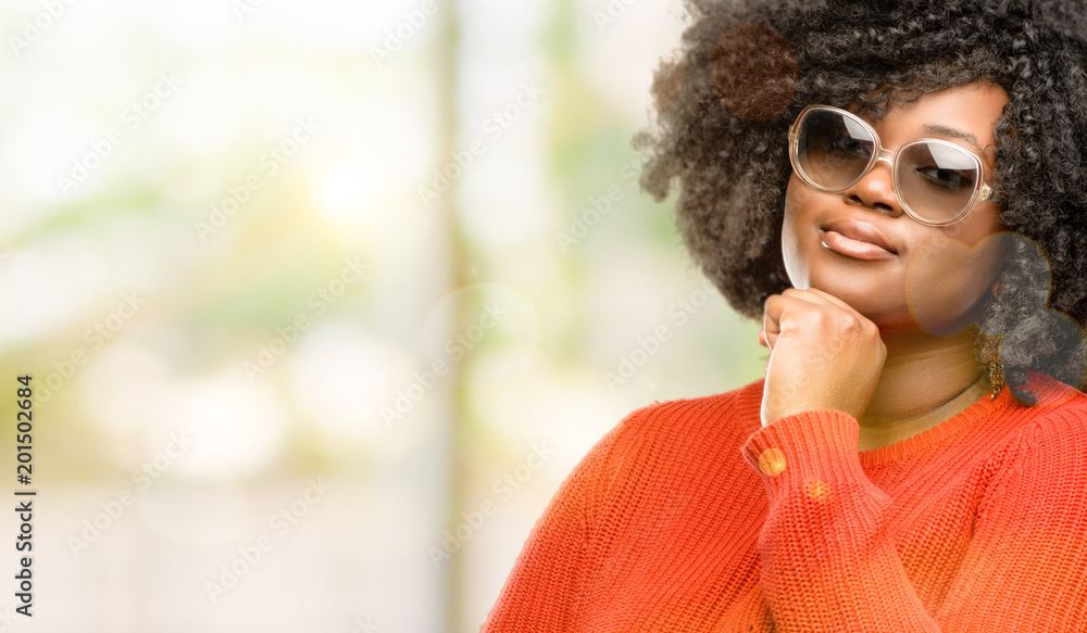 Beautiful african woman thinking and looking up expressing doubt and ...
