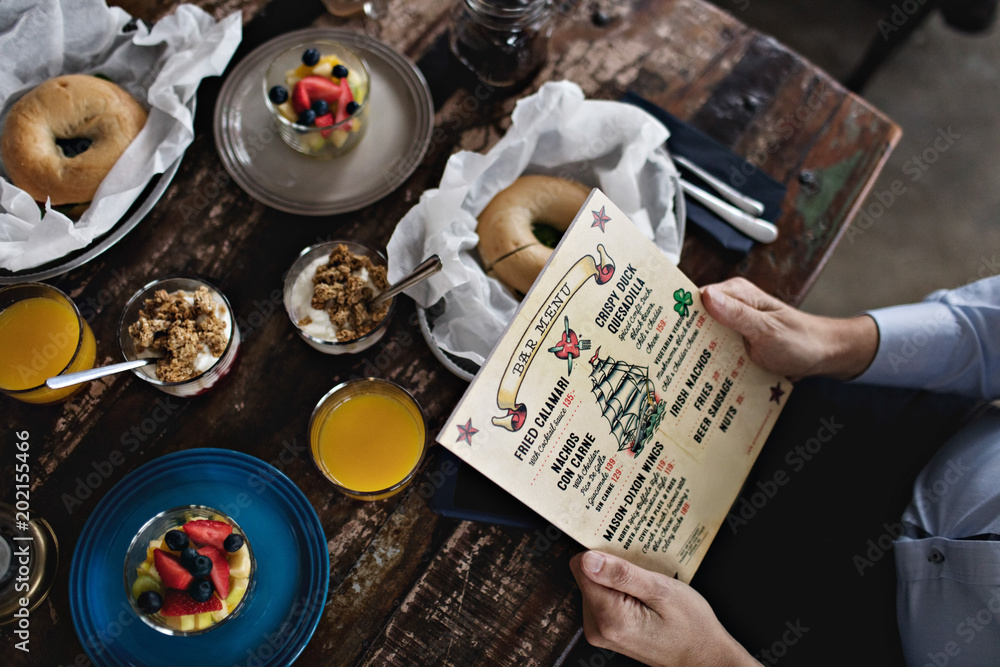Midsection of man holding menu while having brunch at dining table ...