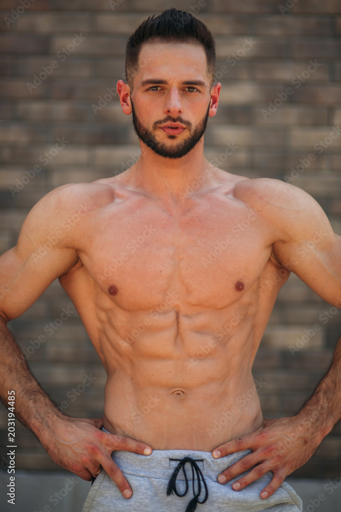 Young athlete posing with a torso for photography on a brick wall ...
