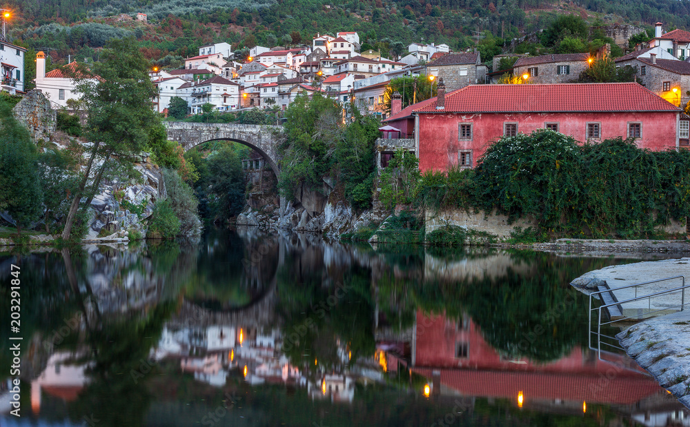 Stone bridge and houses of Avô, in Portugal, with reflections on the ...
