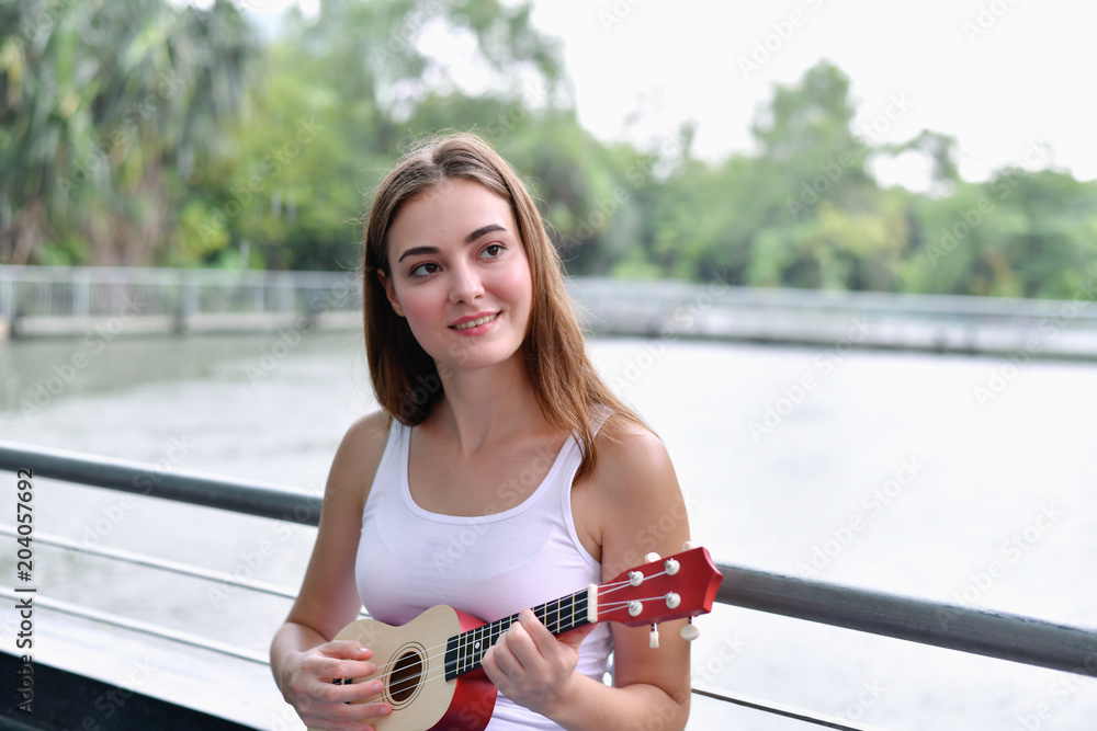 Music Concepts. beautiful girls playing Ukulele. women relaxing with music. women have a happy ...