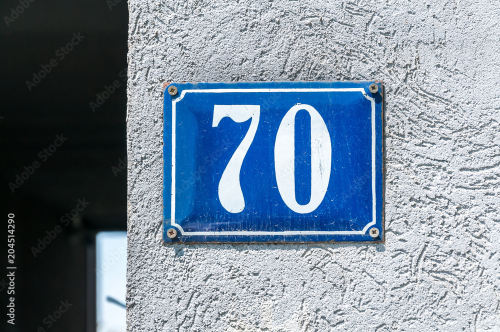 Old vintage house address metal number 70 seventy on the plaster facade ...