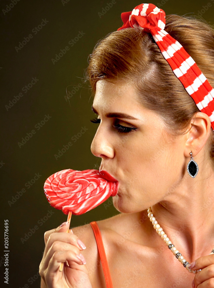 Foto de Stock Woman eating lollipops. Girl in pin-up style hold striped ...