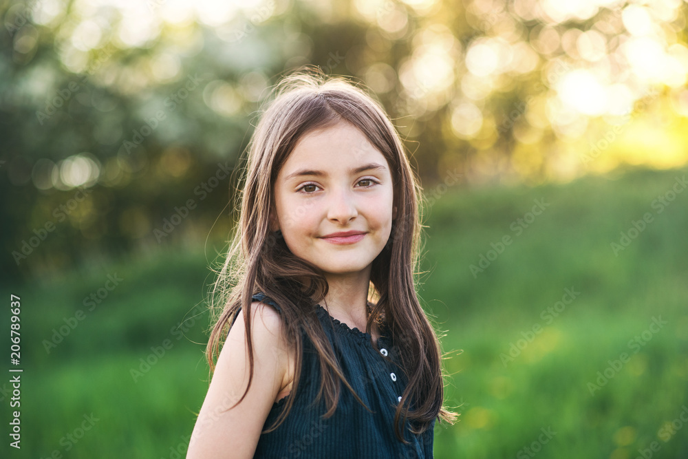 A small girl standing outside in nature. Stock Photo | Adobe Stock