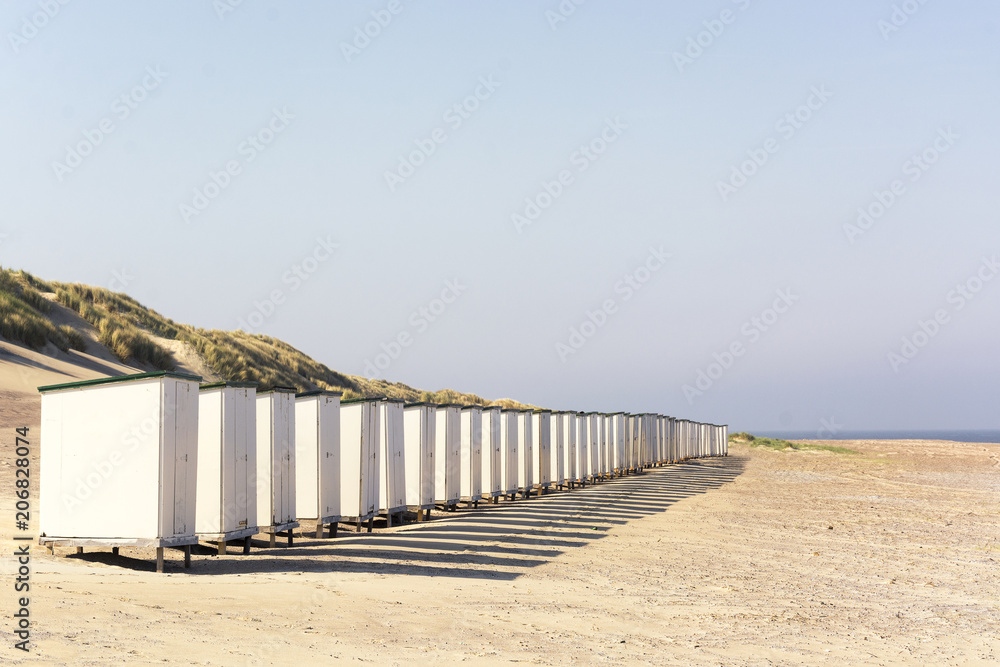 ภาพถ่าย Stock Row of white beach huts on an empty sunny beach in the ...