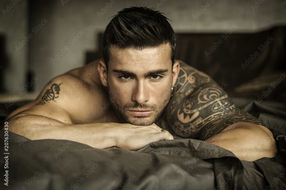 Shirtless muscular sexy male model lying alone on bed in his bedroom ...