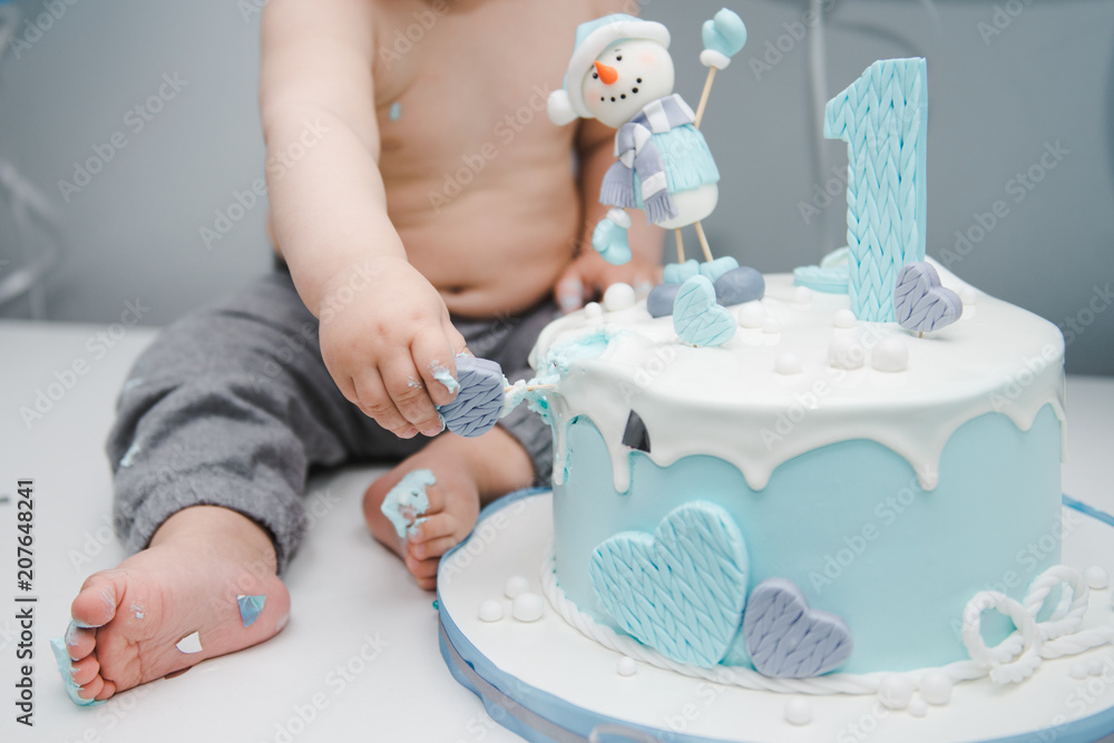Kid's feet near the cake. Cute little boy eating his first birthday ...