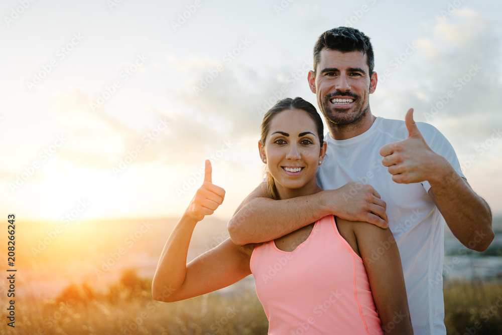 Successful sporty couple of runners doing thumbs up positive gesture ...