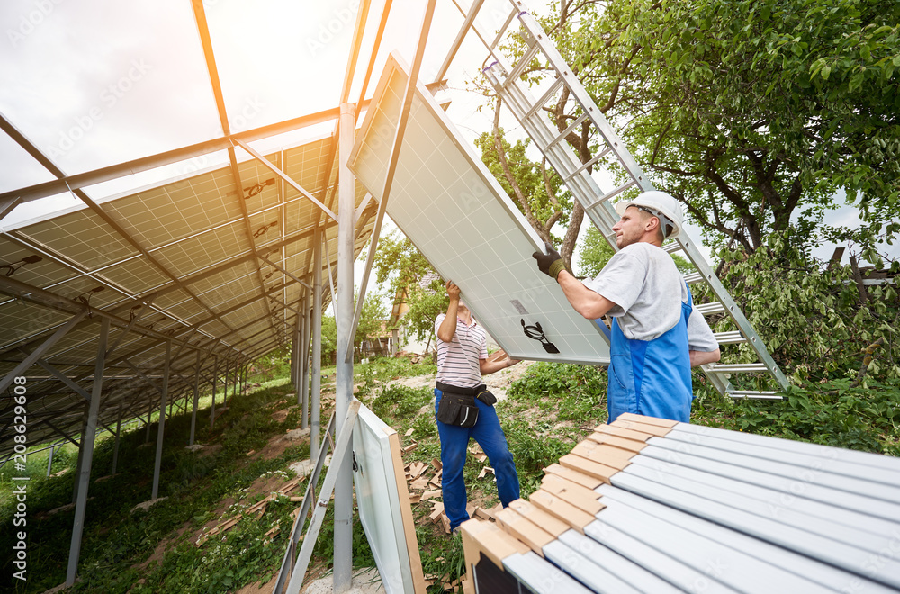 Installing of solar photo voltaic panel system. Two technicians lifting ...