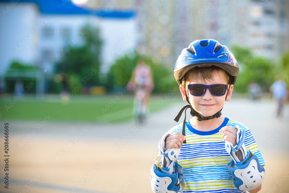 Little boy riding on rollers in the summer in the Park. Happy child in ...