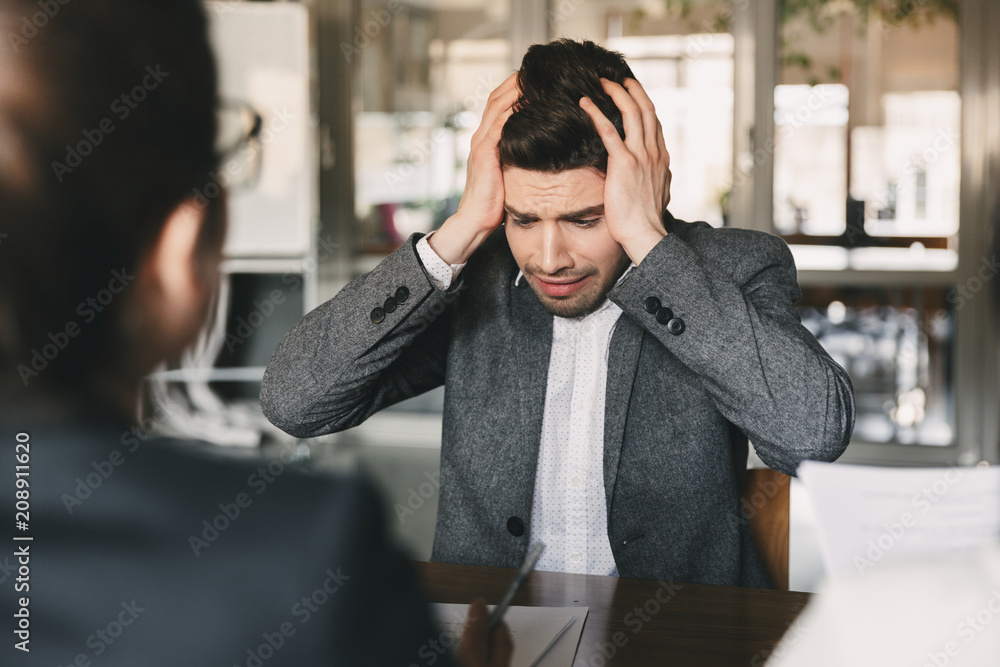 Shocked upset man 30s worrying and grabbing his head during job ...