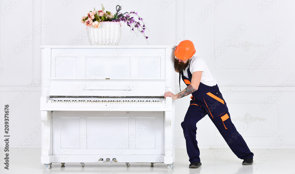 Man with beard worker in helmet and overalls pushes, efforts to move ...