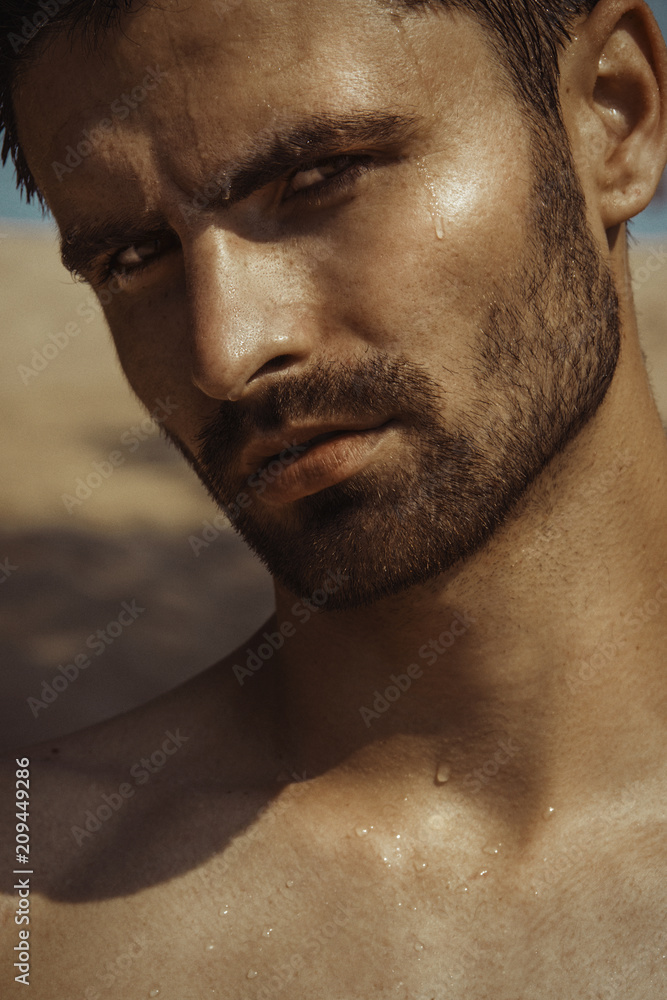 Strong face male model on the nature background with sand and water on ...