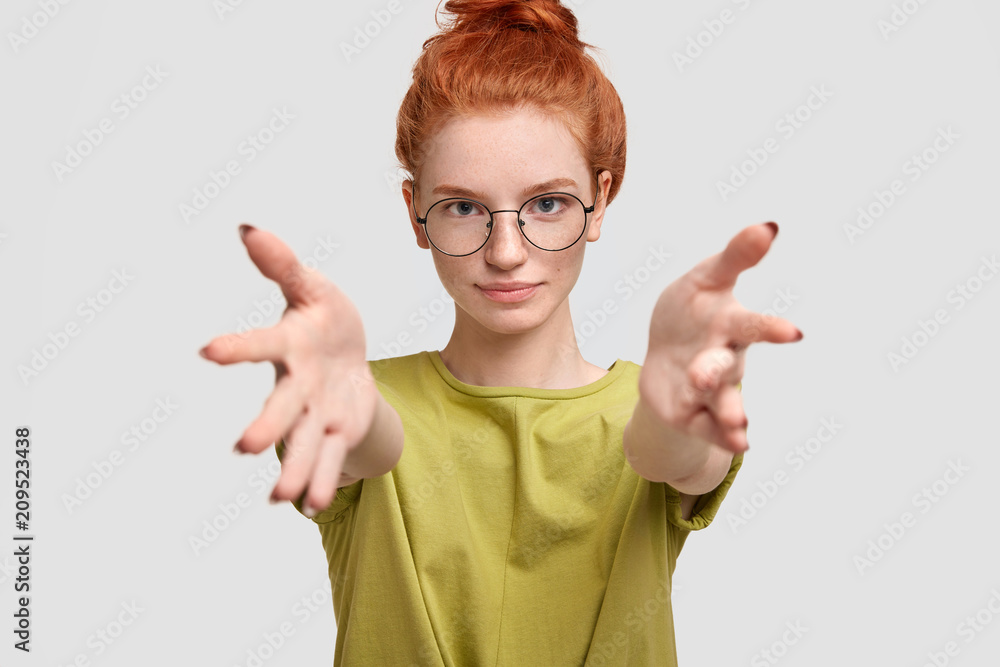 Cropped view of adorable serious freckled ginger female stretches hands ...