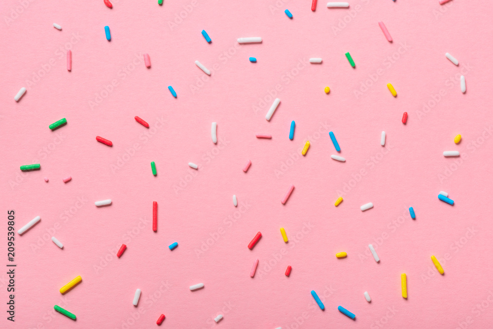 colorful sprinkles over pink background, decoration for cake and bakery ...