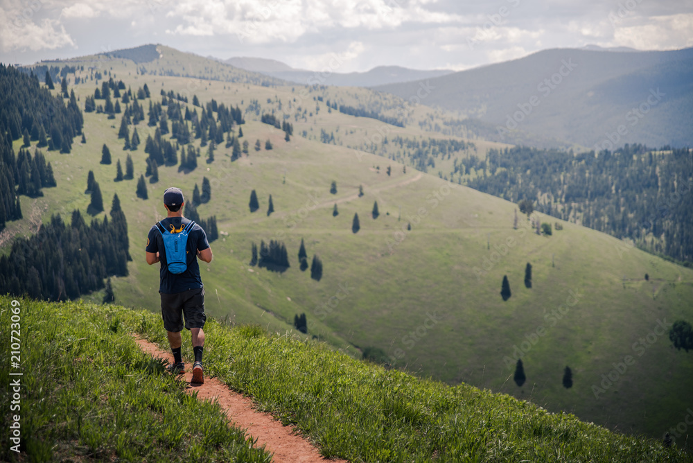 A man hiking on a trail with Vail's back bowls in the background during ...