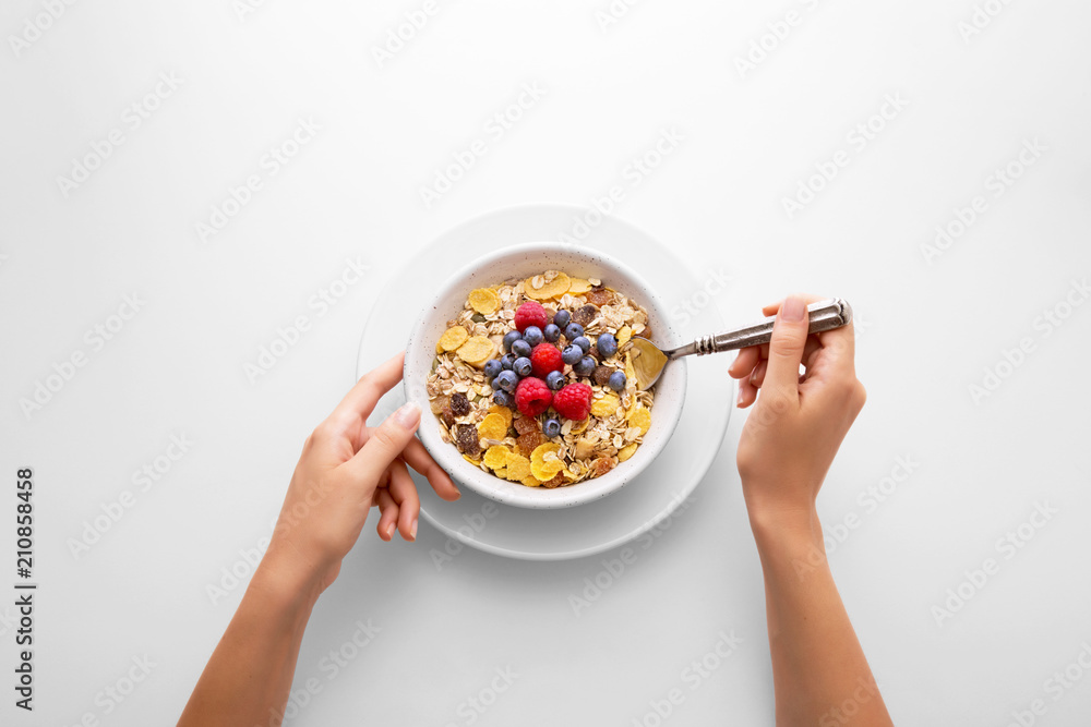 Young woman eating muesli cereal breakfast with berry fruit in a white ...