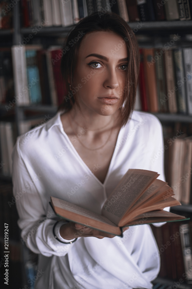 sexy woman in library near bookshelf standing and dreaming. btunette ...