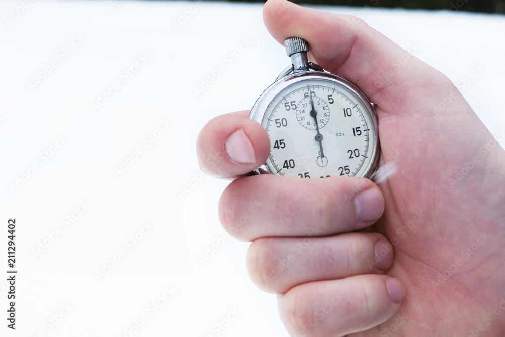One person starting up a stopwatch in hand on a white snow background ...