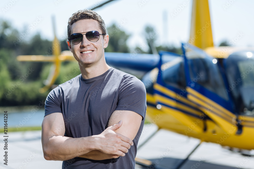 Love my job. Cheerful athletic pilot folding his arms across his chest ...