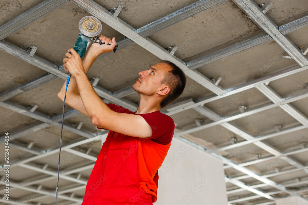 Construction worker assemble a suspended ceiling with drywall and ...