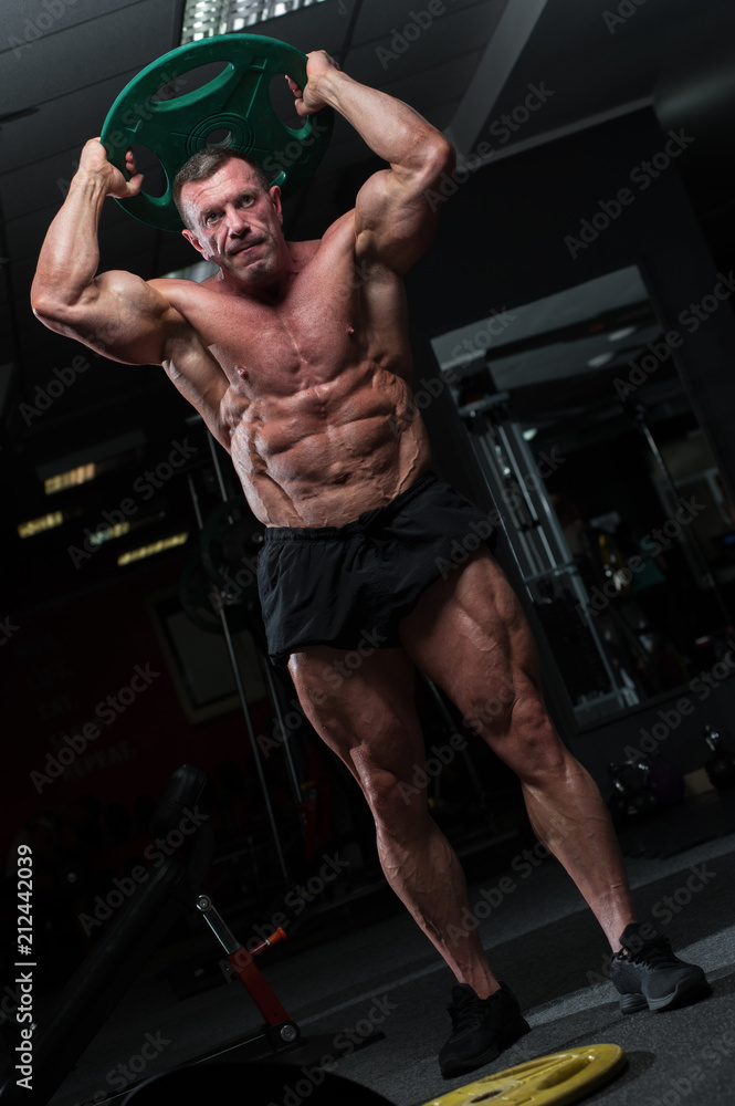 Full length Portrait of high level bodybuilder posing with heavy ...