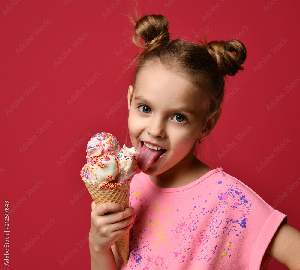 Pretty baby girl kid eating licking big ice cream in waffles cone with ...