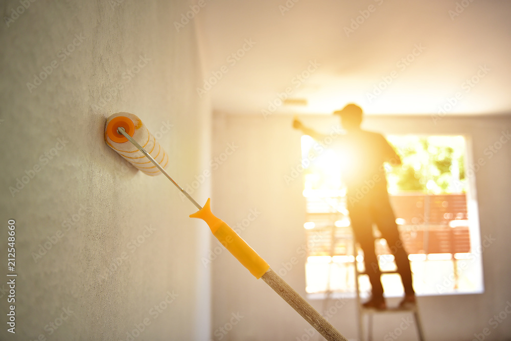 Engineer Construction painter man at work with a paint roller on the ...