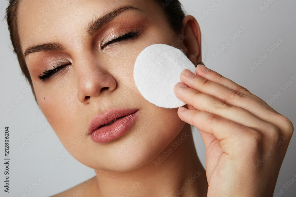 Beautiful girl with big brown eyes and dark eyebrows cleaning skin face ...