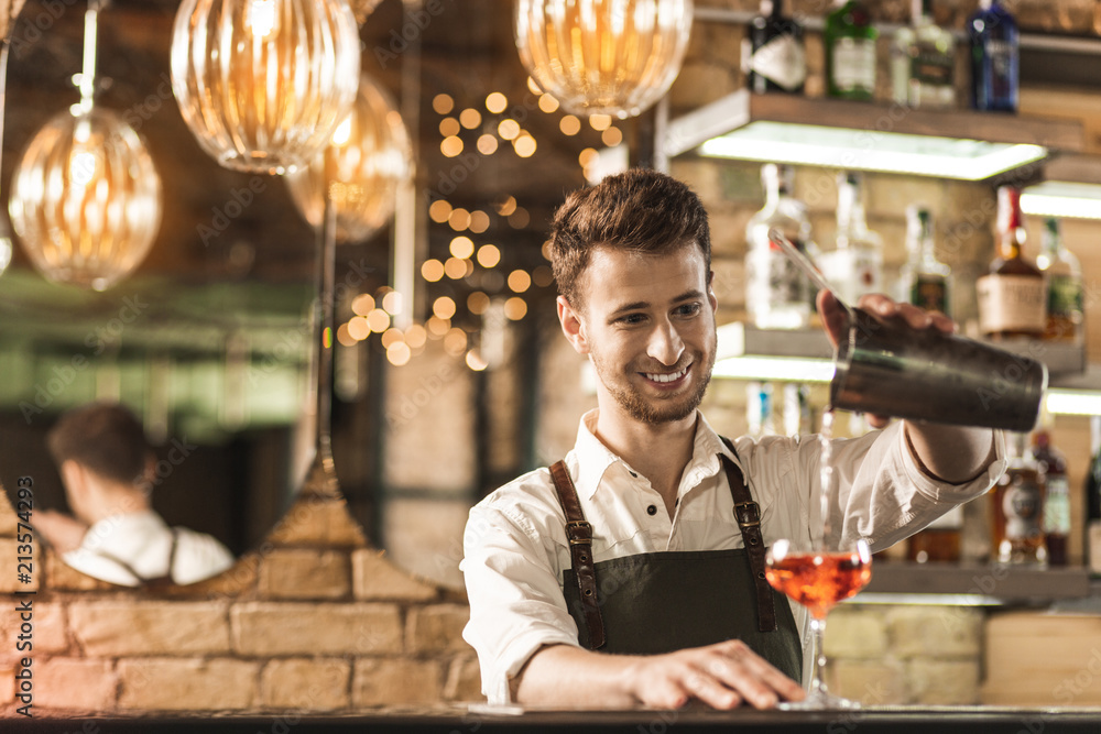 Nice cocktail. Handsome young barman standing behind the bar counter ...